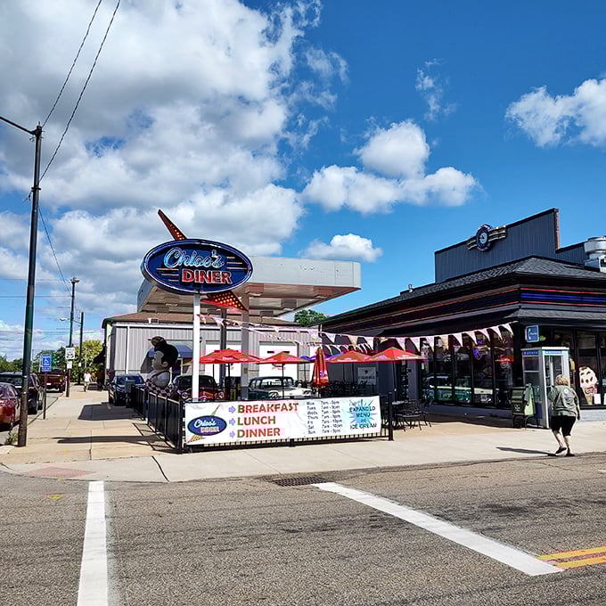 That neon sign isn't just advertising—it's a time portal disguised as a diner. The red umbrellas practically wink at you from the sidewalk.