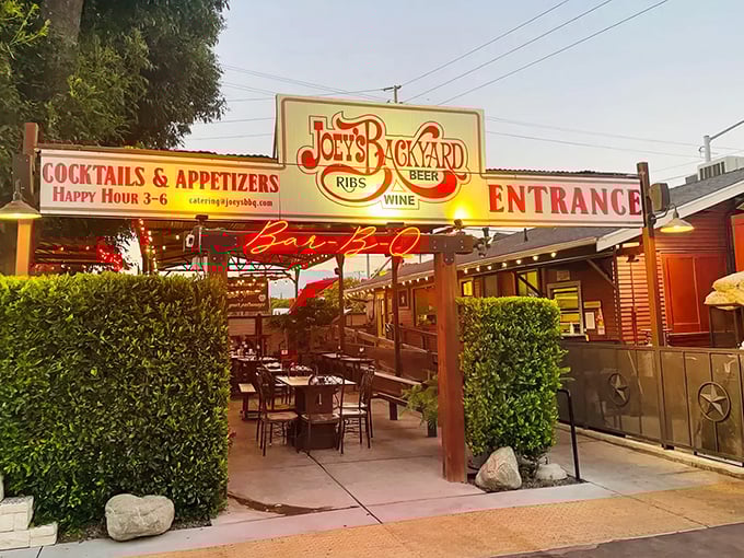 "Joey's Backyard" entrance beckons with neon glow and strategically placed greenery – your portal to barbecue nirvana in Chino.