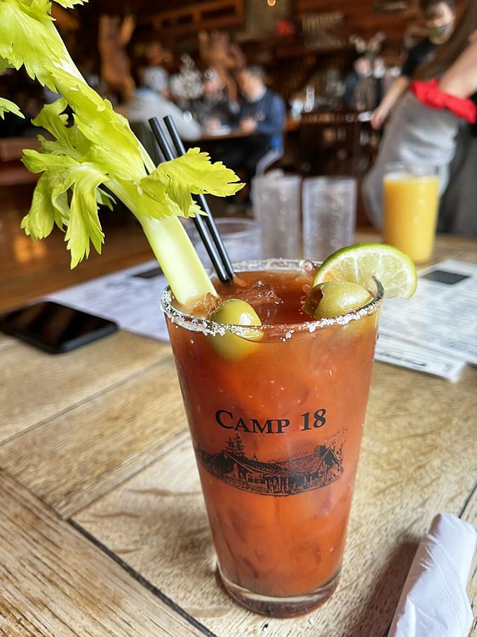 A Bloody Mary with attitude – garnished with celery, olives, and lime in a souvenir glass that screams "Yes, I'm on vacation, even if it's just for lunch."