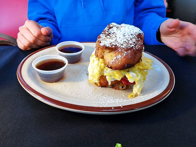 Breakfast reimagined: a powdered sugar-dusted challah bun embracing fluffy eggs. Two dipping sauces because important decisions shouldn't happen before coffee.