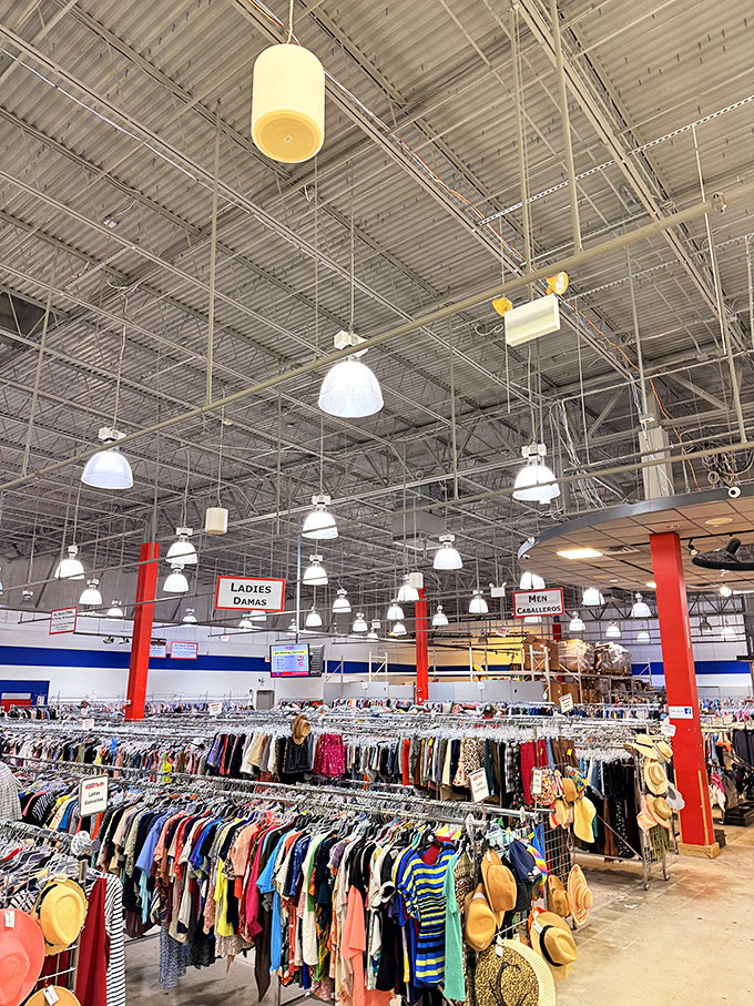 The clothing section stretches toward the industrial ceiling, organized by type and size—a rainbow of fashion possibilities at fraction-of-retail prices.