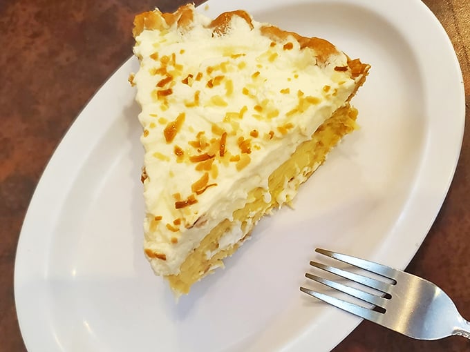 Coconut cream pie with a golden toasted top – the kind that makes you consider ordering dessert at 9 AM because life is short and pie is forever.