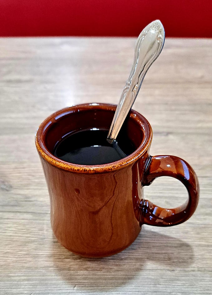 The coffee comes in that perfect diner mug—thick-walled, no-nonsense, ready to transform you from zombie to human being.