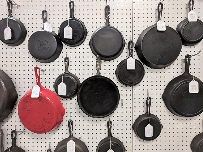 Cast iron cookware hanging like dark medals of culinary honor. That lone red pan is the rebel of the bunch—the Keith Richards of kitchen equipment.