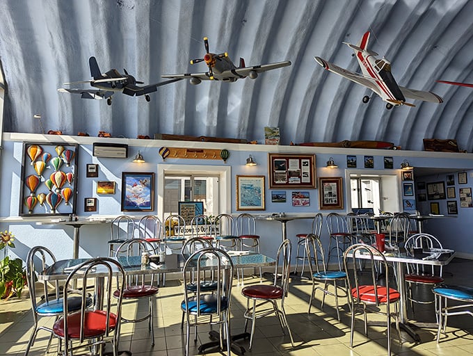 Every seat offers a view of aviation history. The colorful chairs add playful pops against the hangar's industrial backdrop—diner aesthetics with wings.