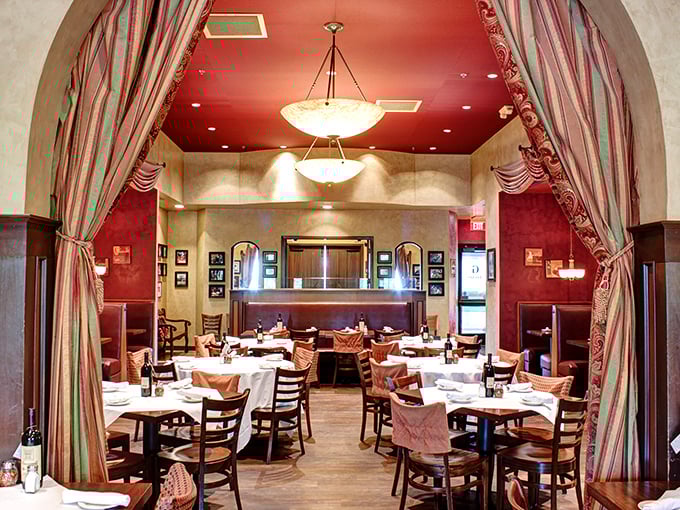 The rich red walls and elegant drapery of this dining section create a theatrical backdrop for the real stars of the show—the plates of pasta heading to eager tables.