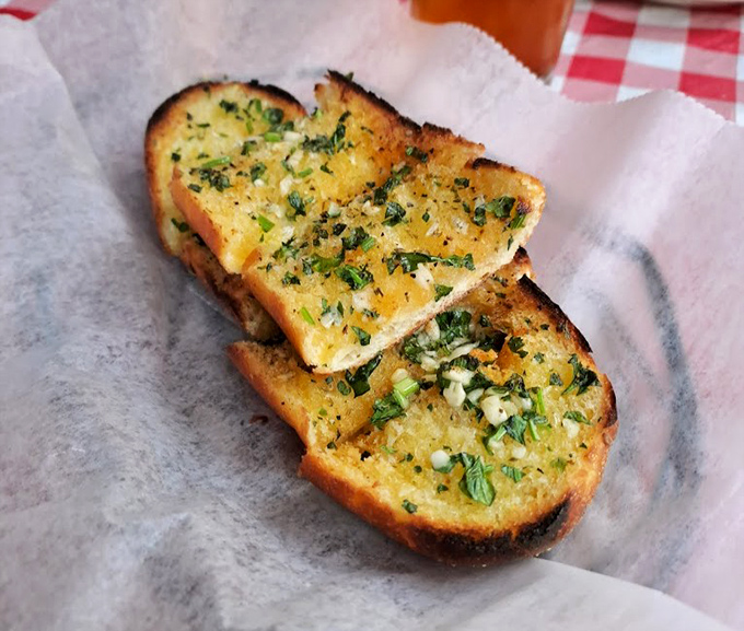 Garlic bread that doesn't whisper but announces its presence – herbaceous, buttery, and worth every moment of post-meal breath mint necessity.