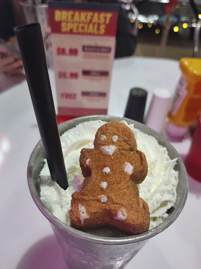 A milkshake topped with a gingerbread man who looks like he's having the time of his life before the inevitable plunge.