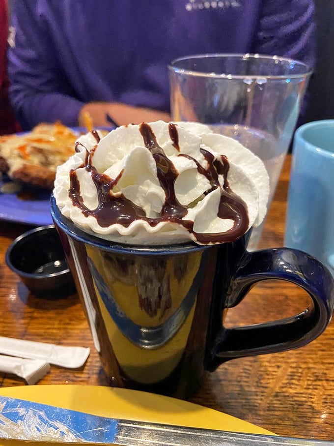 Hot chocolate topped with whipped cream and chocolate drizzle – basically dessert disguised as a morning beverage.