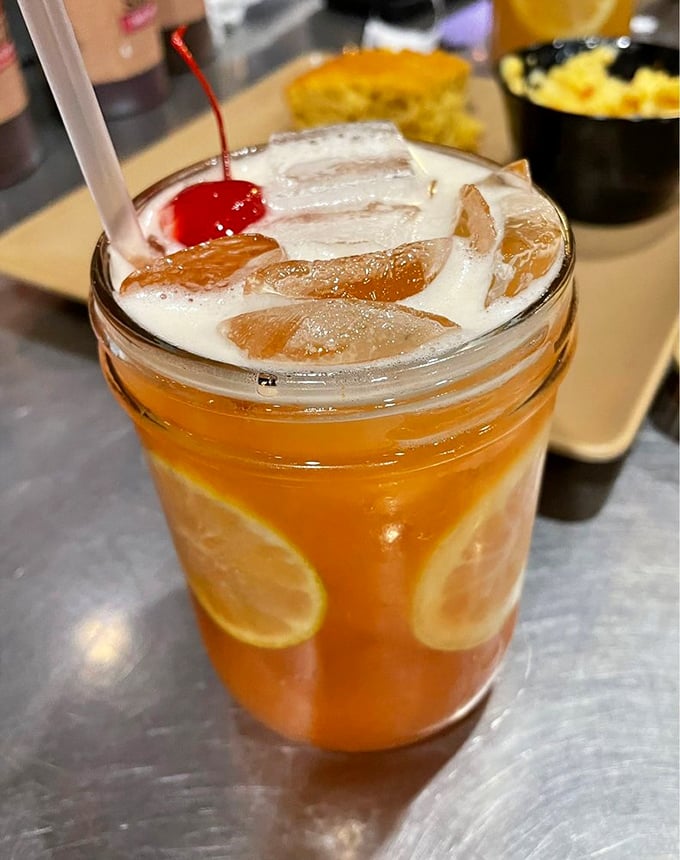 A cocktail that's dressed for vacation – citrus, ice, and a cherry on top, like liquid sunshine waiting to brighten your barbecue experience.