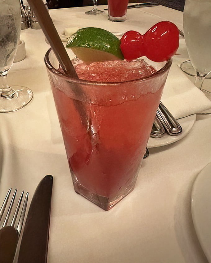 A ruby-red cocktail garnished with lime and cherries – proof that what happens before the steak can be just as important as the main event.