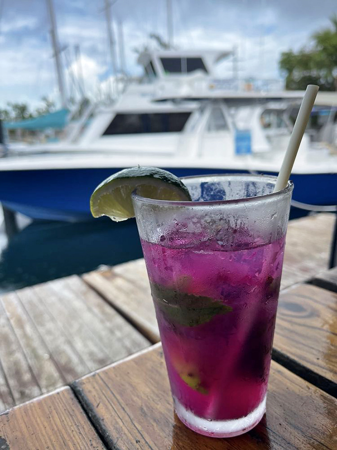 Nothing says "vacation mode activated" like a vibrant purple cocktail with boats in the background. The lime isn't garnish—it's essential equipment.