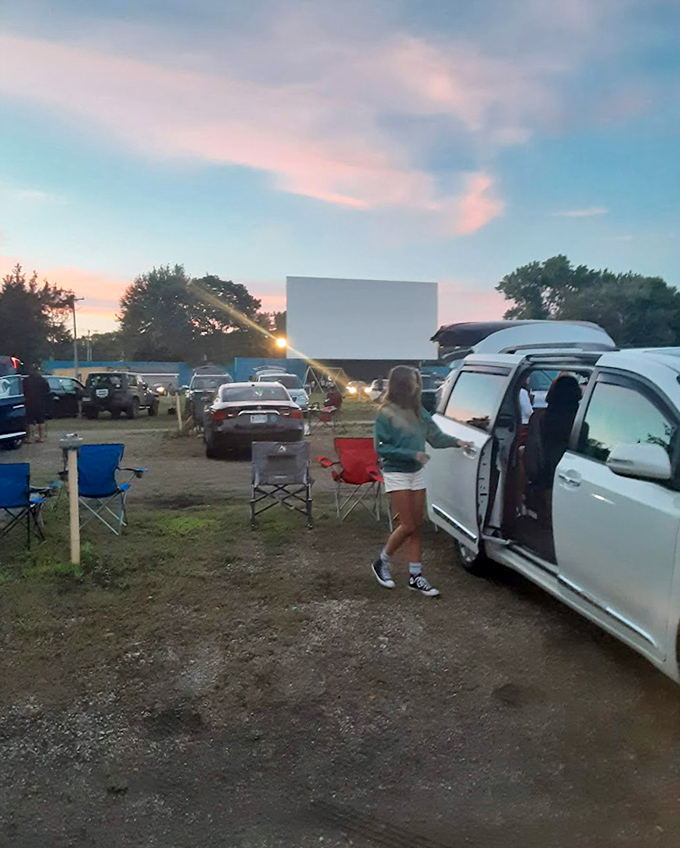 Sunset paints the sky in pastels as moviegoers prepare their vehicular nests—some already opening doors to summer's perfect evening.