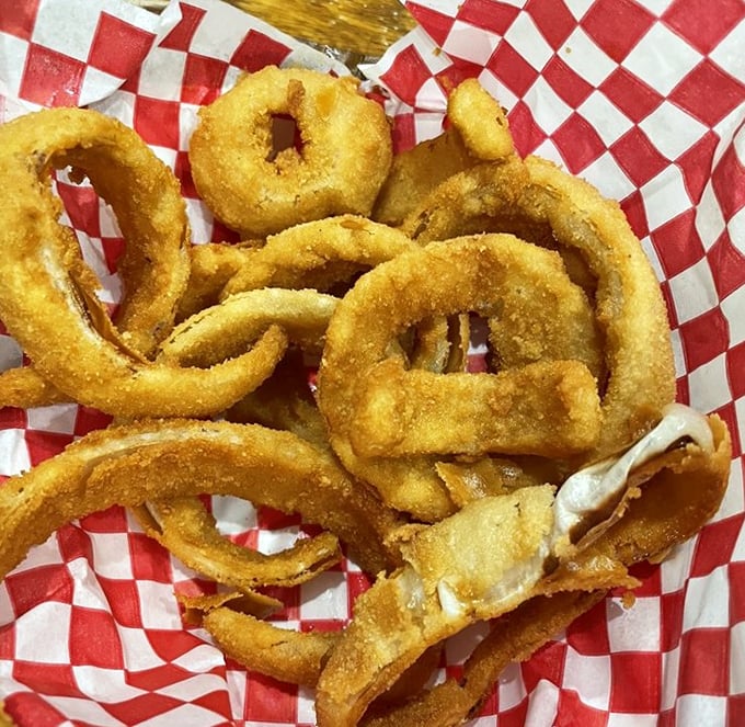 Onion rings with that perfect crunch-to-softness ratio, nestled in a red checkered basket that signals you're about to experience something authentic.