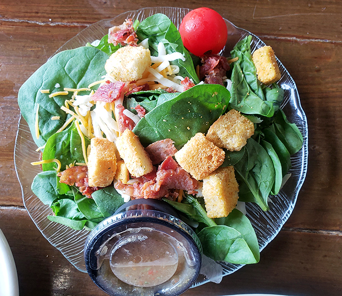 Even the salad gets the coastal treatment with fresh greens, cheese, and what appears to be bacon – because vegetables should never be boring.