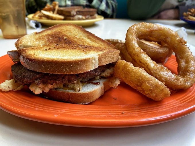 This sandwich and onion ring duo isn't just lunch—it's edible therapy after a long morning, served on a bright orange plate that matches your mood after the first bite.