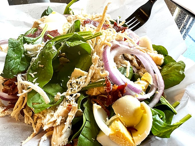 A spinach salad that doesn't apologize for being healthy—it's too busy showing off its perfectly cooked chicken and farm-fresh eggs.