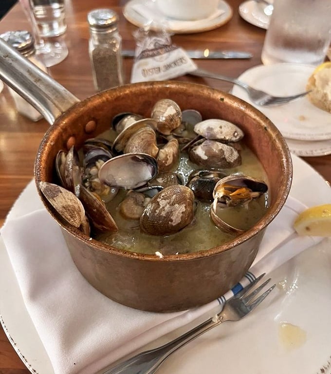 Steamed clams swimming in garlicky broth—a copper pot of treasures from the deep. Each shell opens to reveal tender morsels worth savoring.