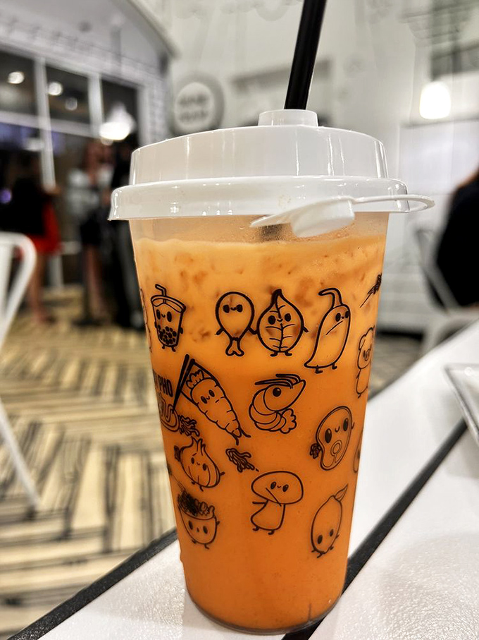 Thai tea in a cup adorned with adorable cartoon characters. This creamy, orange elixir is the perfect cooling counterpoint to spicy noodles.