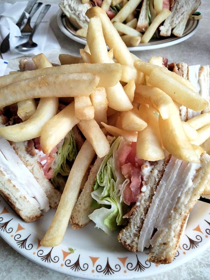 Behold the turkey club in its natural habitat – surrounded by crispy fries and waiting to be devoured. This isn't just lunch; it's edible nostalgia on a decorative plate.