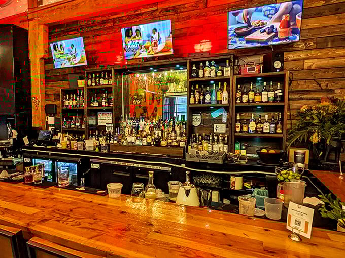 The bar at AKADI isn't just stocked with spirits – it's a liquid library of possibilities, backed by warm wood that glows like sunset.