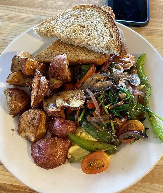 Roasted potatoes that crackle with flavor alongside sautéed vegetables and toast – proof that simple ingredients can create extraordinary experiences.