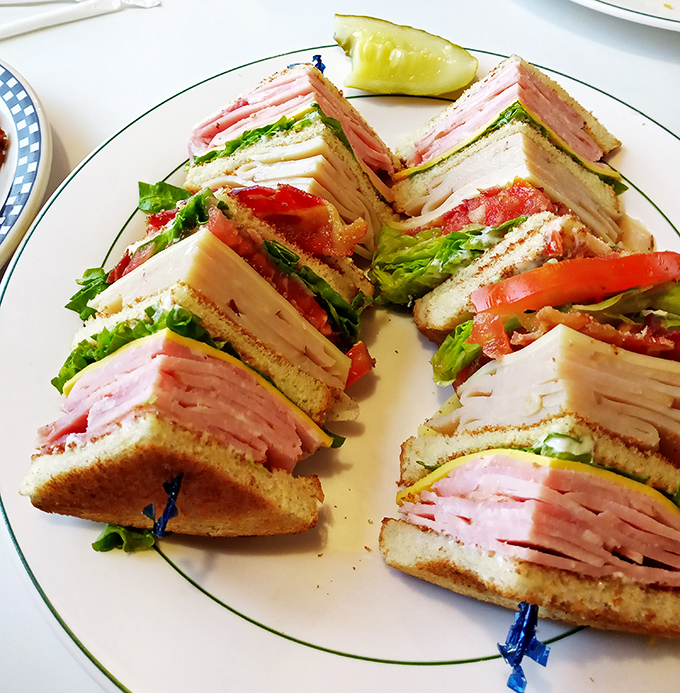 The club sandwich—a skyscraper of deli meat architecture that requires both hands, several napkins, and absolutely no regrets.