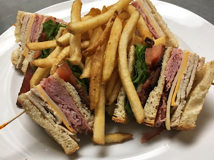 The club sandwich—that reliable triple-decker masterpiece where turkey, bacon, and bread achieve perfect harmony, with fries playing the delicious supporting role.