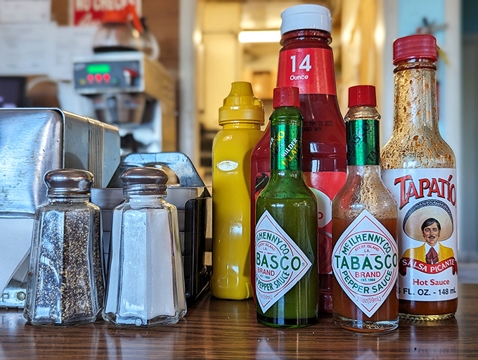The condiment lineup—where every hot sauce bottle tells a story of meals transformed from good to "I need a moment alone."