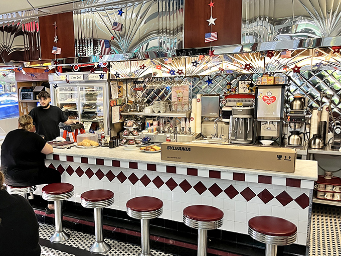 The beating heart of any great diner—a counter where strangers become neighbors over eggs and coffee. Those red stools have heard it all.