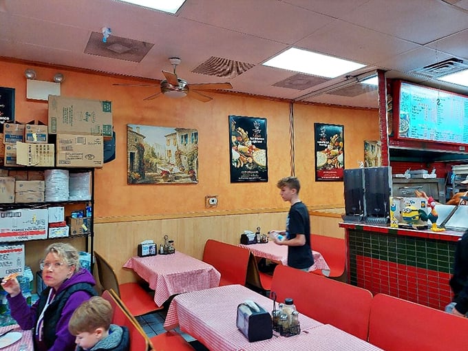 The dining room tells the real story—families and friends gathered around red-checkered tables, participating in the universal ritual of breaking bread together.