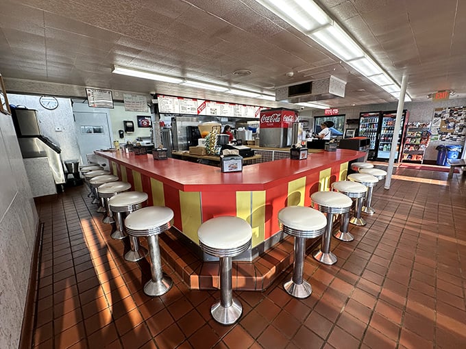 The counter where magic happens—red and yellow like a vintage carnival, with stools that have supported generations of happy eaters.