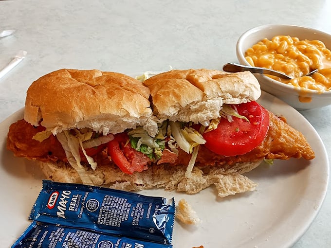 A sandwich symphony on a plate – crispy fish nestled in a pillowy roll with fresh tomatoes and crisp lettuce, while mac and cheese stands by as the perfect supporting act.