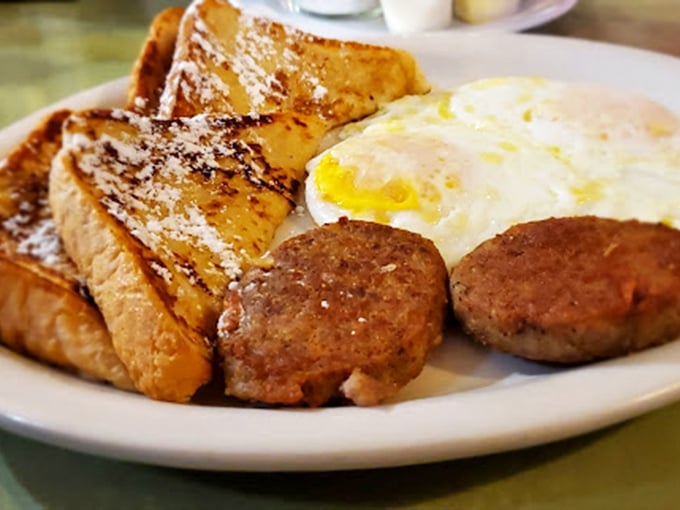 French toast dusted with powdered sugar alongside sausage and eggs—the breakfast trinity that converts even the most devoted lunch enthusiasts.
