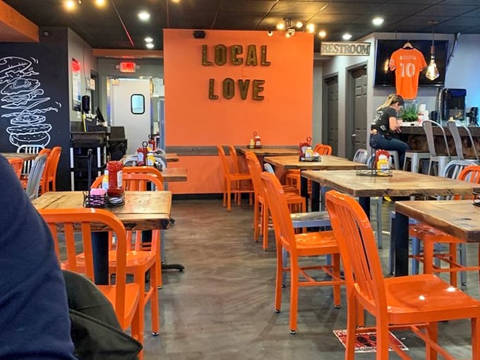 Orange chairs pop against dark walls adorned with "LOCAL LOVE" – a restaurant that wears its heart on its sleeve and its burgers.