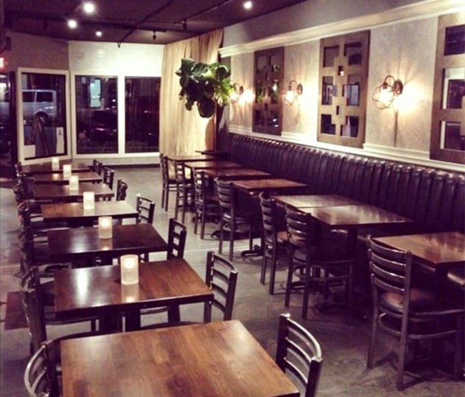 Evening ambiance done right – simple wooden tables, banquette seating, and just enough lighting to see your food without losing the mood.