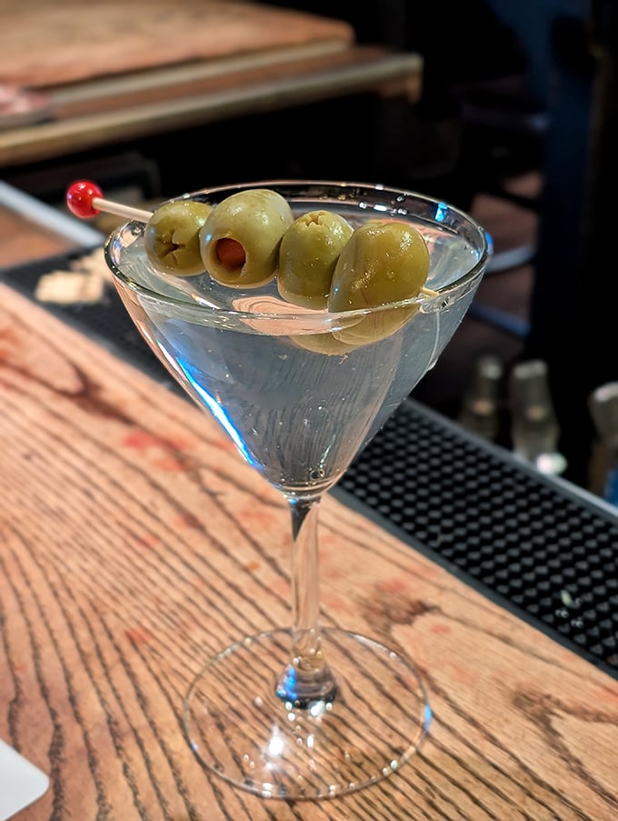 A classic martini with olives, served with the kind of precision that makes James Bond look sloppy. Shaken, stirred, or however—it's perfection.