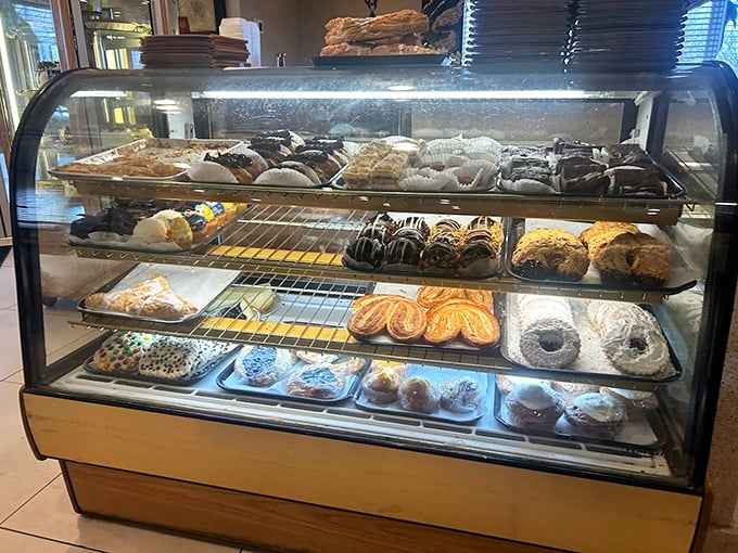 The pastry case—a glass-enclosed museum of baked temptations. Each shelf displays edible art that makes waiting for a table almost pleasurable.