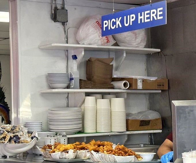 Organization is key in a busy seafood joint. This "Pick Up Here" station keeps hungry patrons moving like a well-oiled fishing vessel.