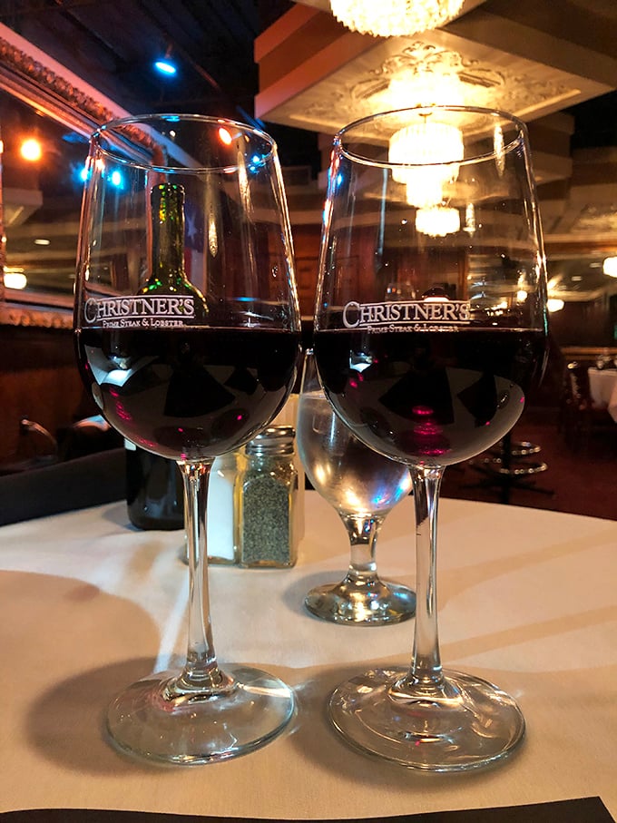 Two glasses of red wine catching the chandelier's glow—a toast to decisions well made in an evening that's just beginning to unfold.