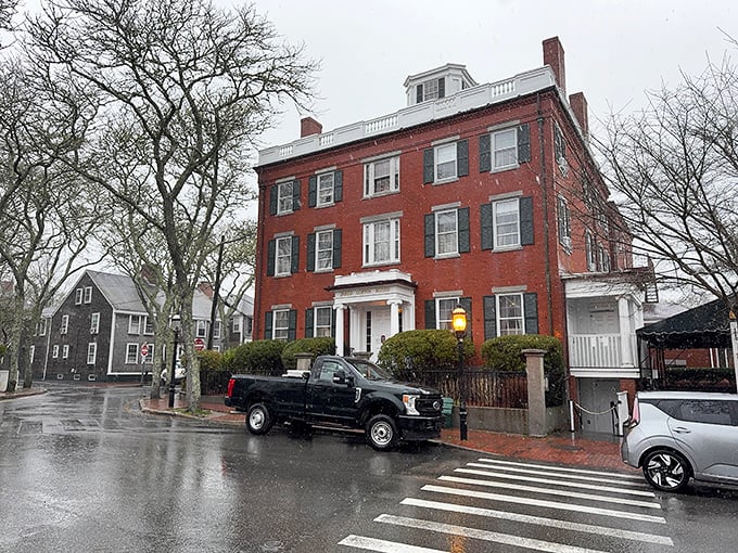 A rainy day in Nantucket adds a moody atmosphere to the historic streetscape. The brick building's white trim pops against the gray sky.