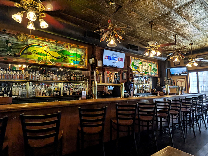 The bar area gleams with promise, backed by stunning stained glass that filters light through scenes of Irish countryside – liquid art behind liquid art.