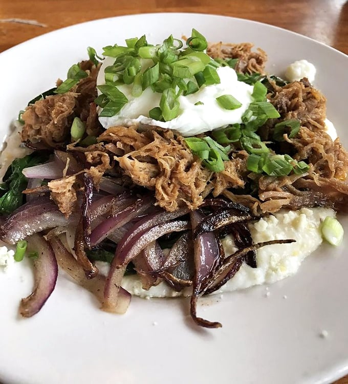 Slow-cooked meat atop creamy grits with caramelized onions – Southern comfort reimagined with the finesse of a culinary artist.
