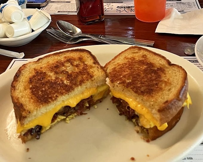 A breakfast sandwich cut to reveal its secrets—like a delicious archaeological dig revealing layers of morning happiness between perfectly toasted bread.