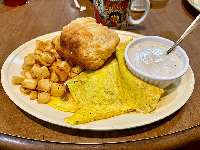 Breakfast perfection on a plate – golden eggs, home fries with purpose, and a biscuit that could float away if not weighed down by gravy.