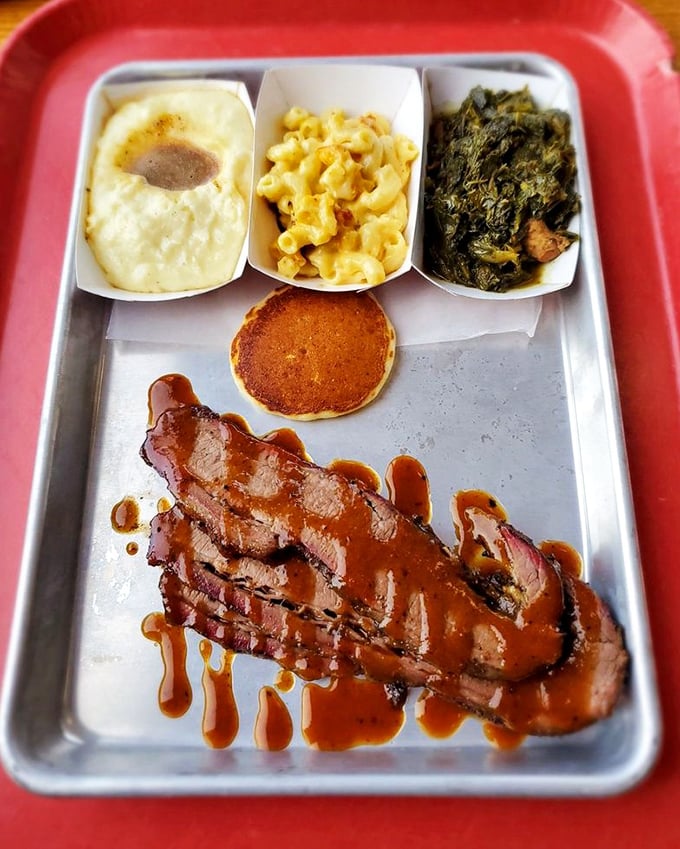 Brisket bathed in gravy alongside mac and cheese, greens, and cornbread—a meat-and-three symphony on a cafeteria tray.