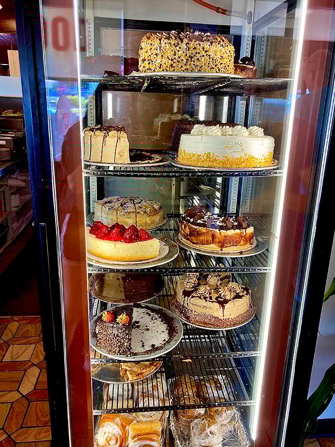 The cake display case – where diet resolutions go to die and birthday wishes come true. Each shelf holds a different definition of happiness.