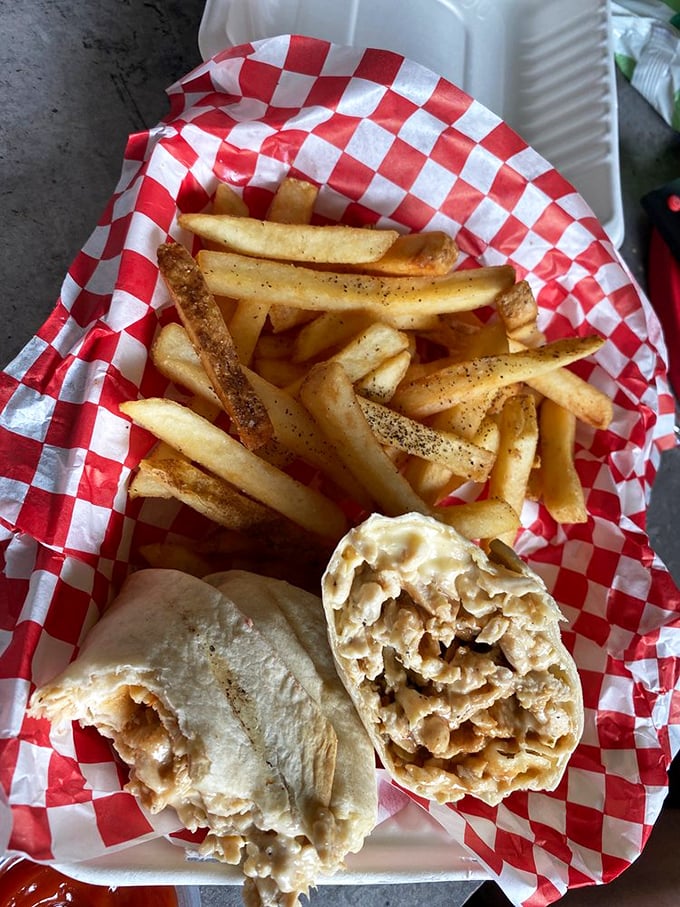 A cheesesteak with fries isn't just a meal—it's a Pennsylvania tradition served on classic red and white checkered paper.