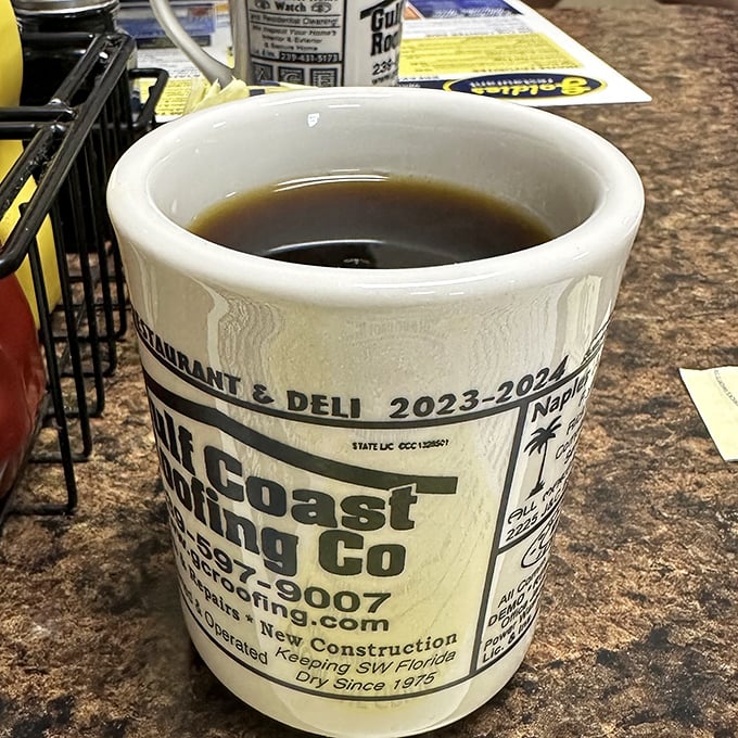 The coffee comes in mugs advertising local businesses—a charming touch that reminds you this is a place where community still matters.