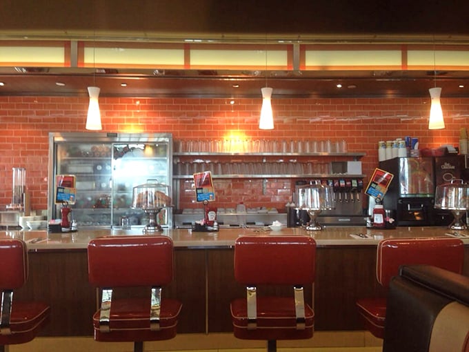 Classic counter seating with those iconic red chairs—where solo diners become temporary family and coffee refills appear like magic.